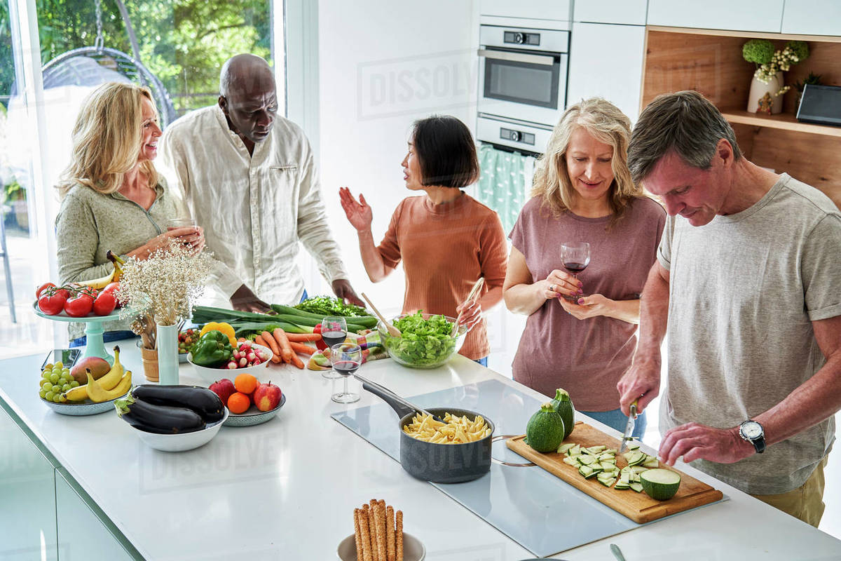 Group of seniors friends gathered at kitchen while preparing dinner ...