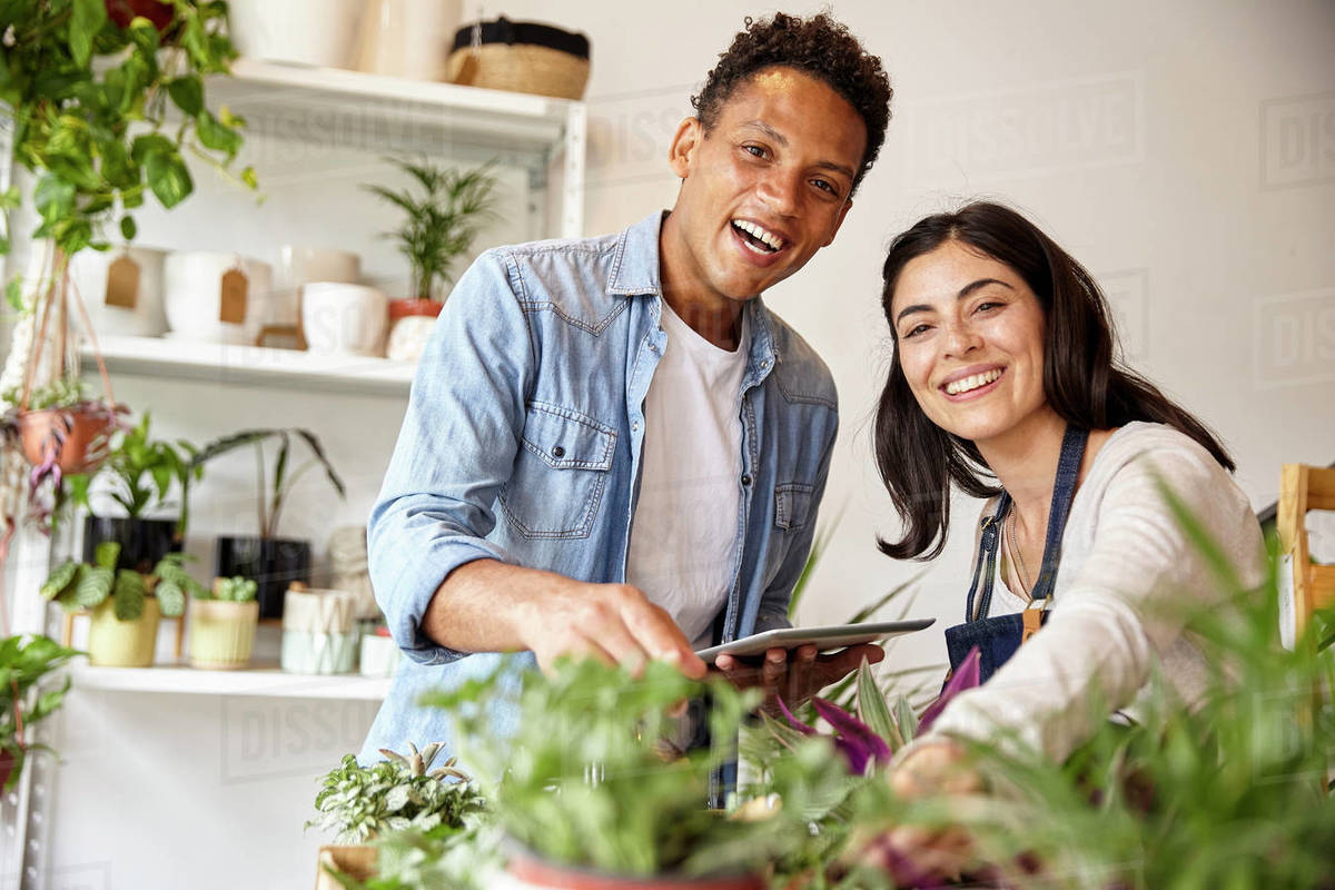 Small business plant shop owners looking at the camera while holding ...