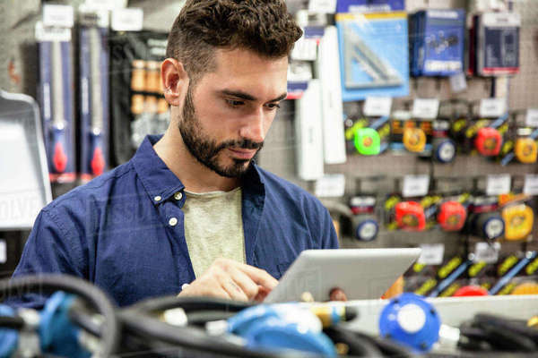 Male hardware shop owner taking inventory on digital tablet - Stock ...