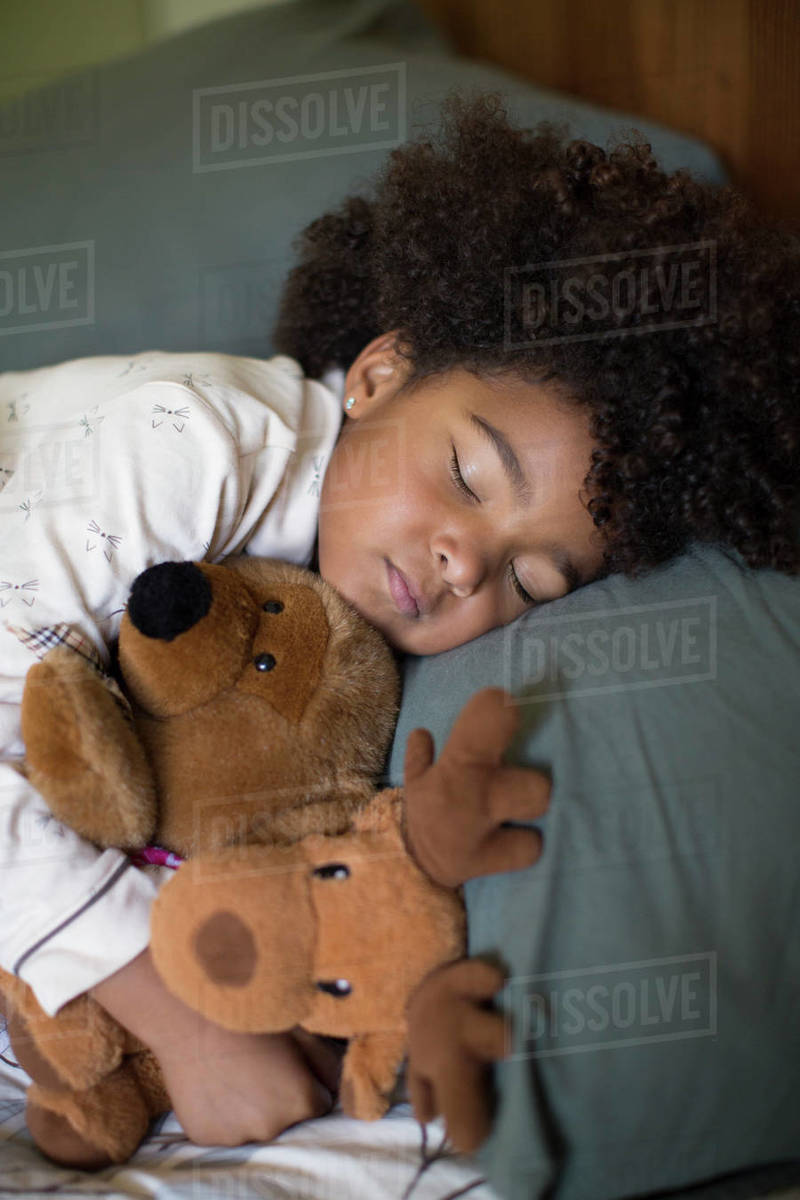 Girl sleeping with toy on bed - Royalty-free Stock Photo | Dissolve