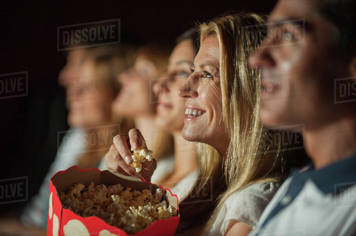 Woman eating popcorn while watching movie in theater - Royalty-free ...