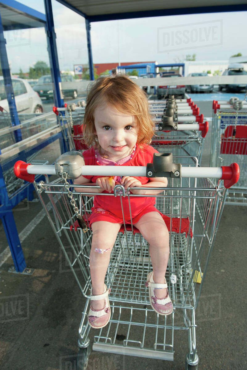 Little girl sitting in shopping cart - Royalty-free Stock Photo | Dissolve