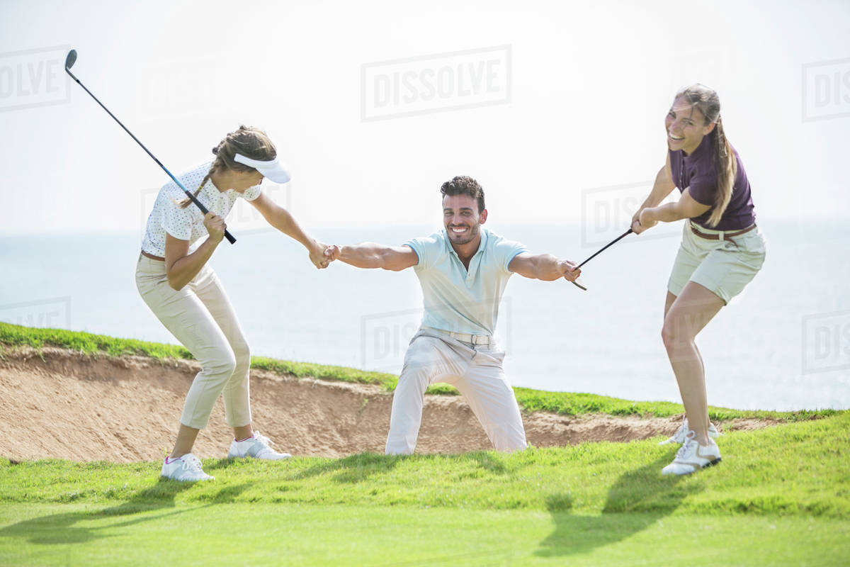 Women pulling man out of sand trap on golf course - Royalty-free Stock ...