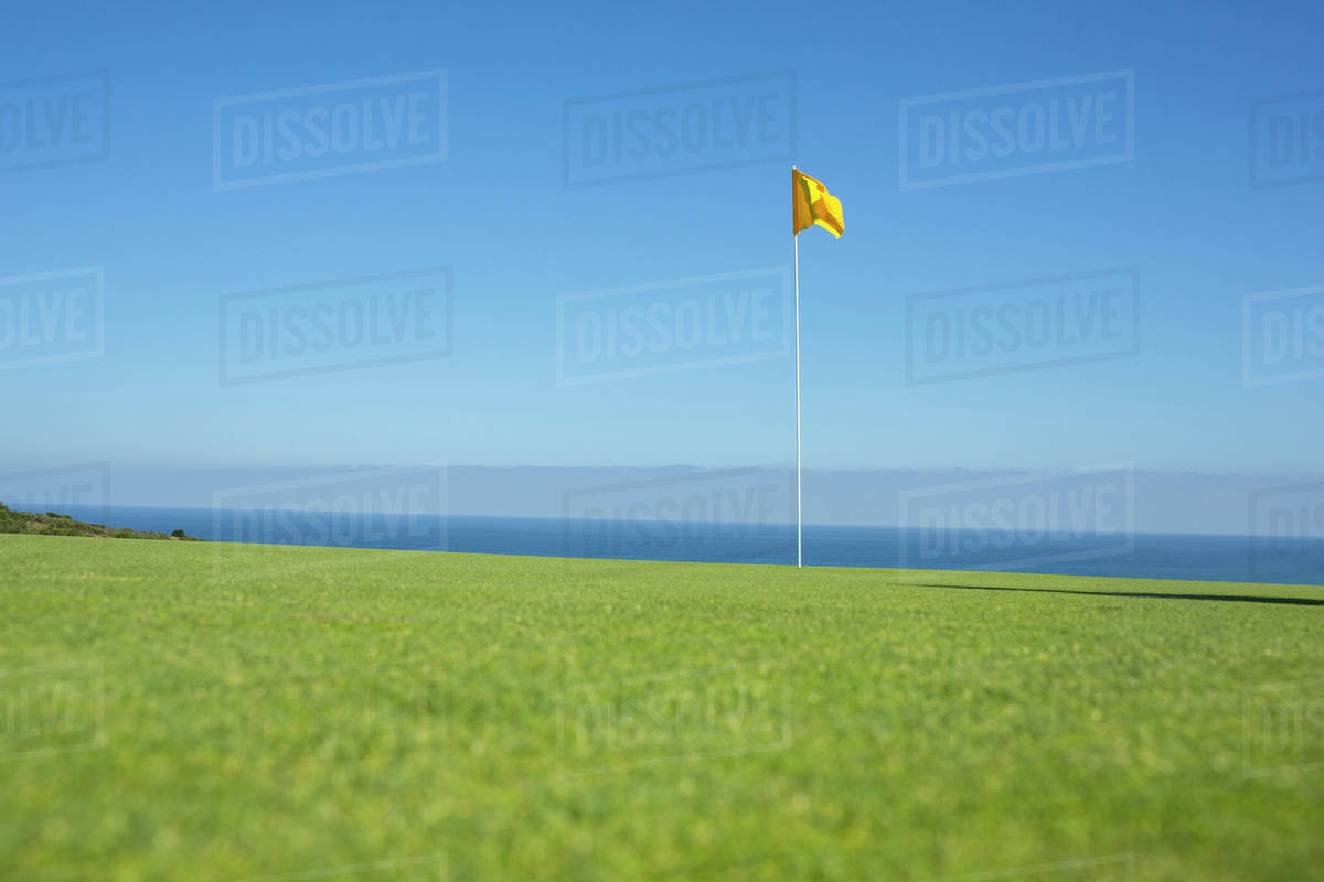 Flag on golf course overlooking ocean - Royalty-free Stock Photo | Dissolve