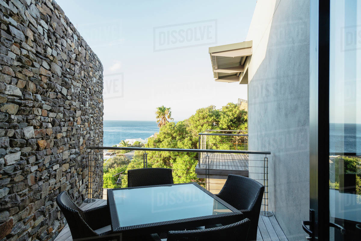 Table and chairs on luxury balcony overlooking ocean - Royalty-free ...