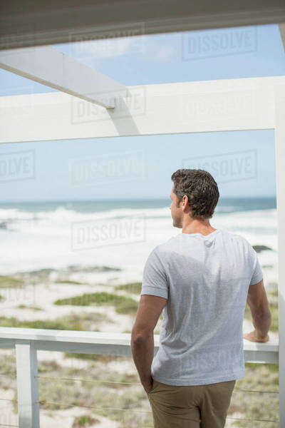 Man looking at ocean view from balcony - Stock Photo - Dissolve