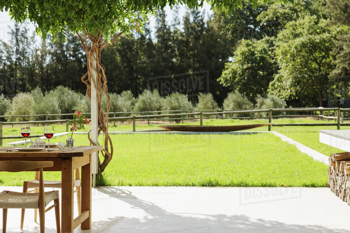 Dining table and chairs on patio overlooking backyard - Stock Photo ...