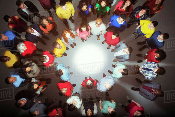 Diverse crowd standing around bright light - Stock Photo - Dissolve