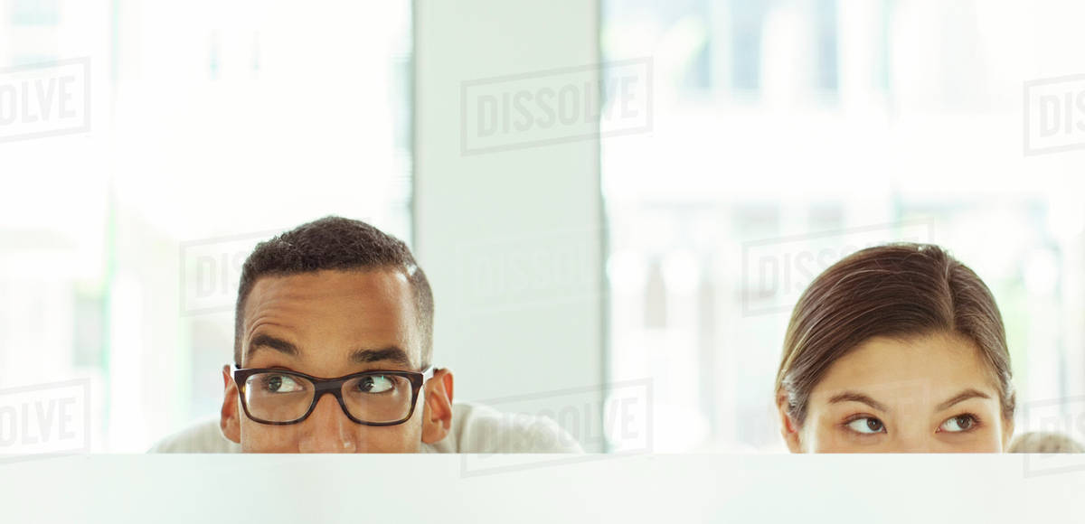 People peeking over cubicle in office - Stock Photo - Dissolve