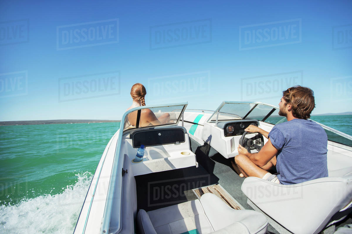 Man steering boat on water with girlfriend - Stock Photo - Dissolve