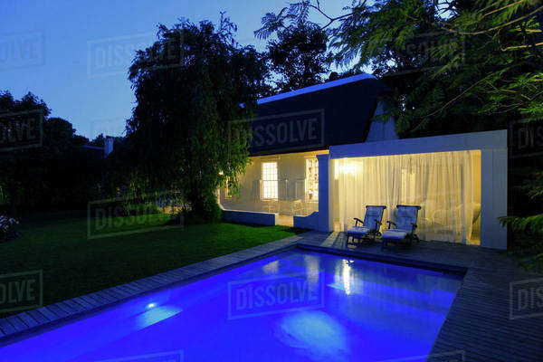 Modern house overlooking illuminated swimming pool at night - Royalty ...