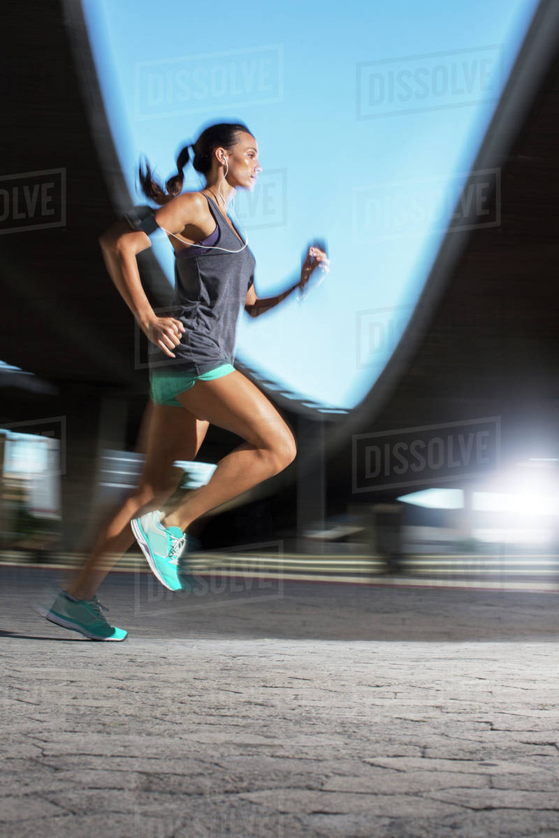 Woman running through city streets - Stock Photo - Dissolve