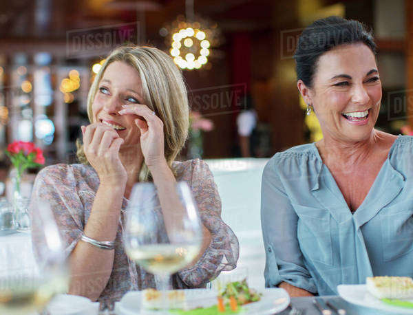 Women laughing at table in restaurant - Stock Photo - Dissolve