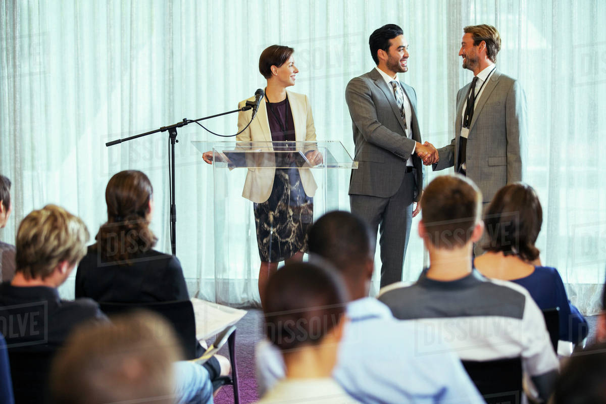 Businessmen shaking hands during presentation in conference room ...