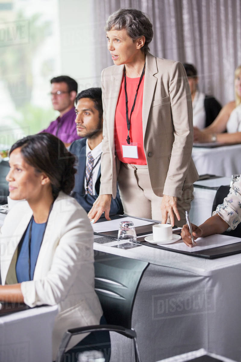 Businesswoman standing and asking question during presentation in ...