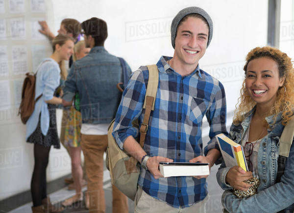 Portrait of two smiling university students standing in corridor ...