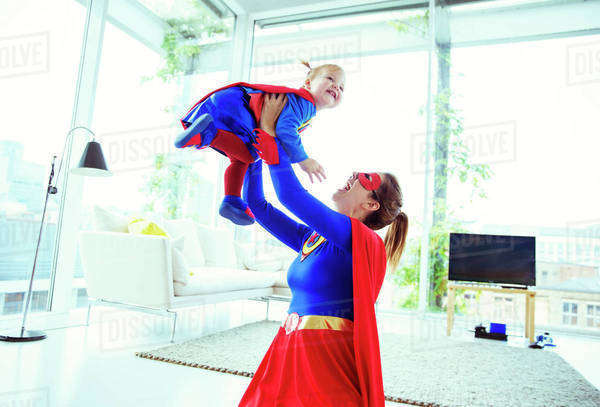 Superhero playing with baby in living room - Stock Photo - Dissolve