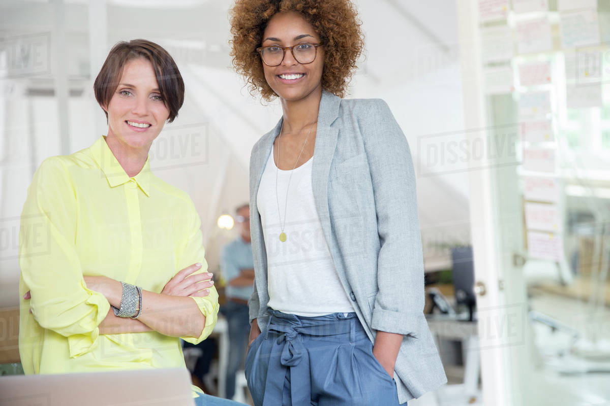 Portrait of female colleagues smiling in office - Stock Photo - Dissolve