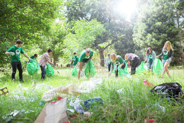 Environmentalist volunteers picking up trash in field - Royalty-free ...