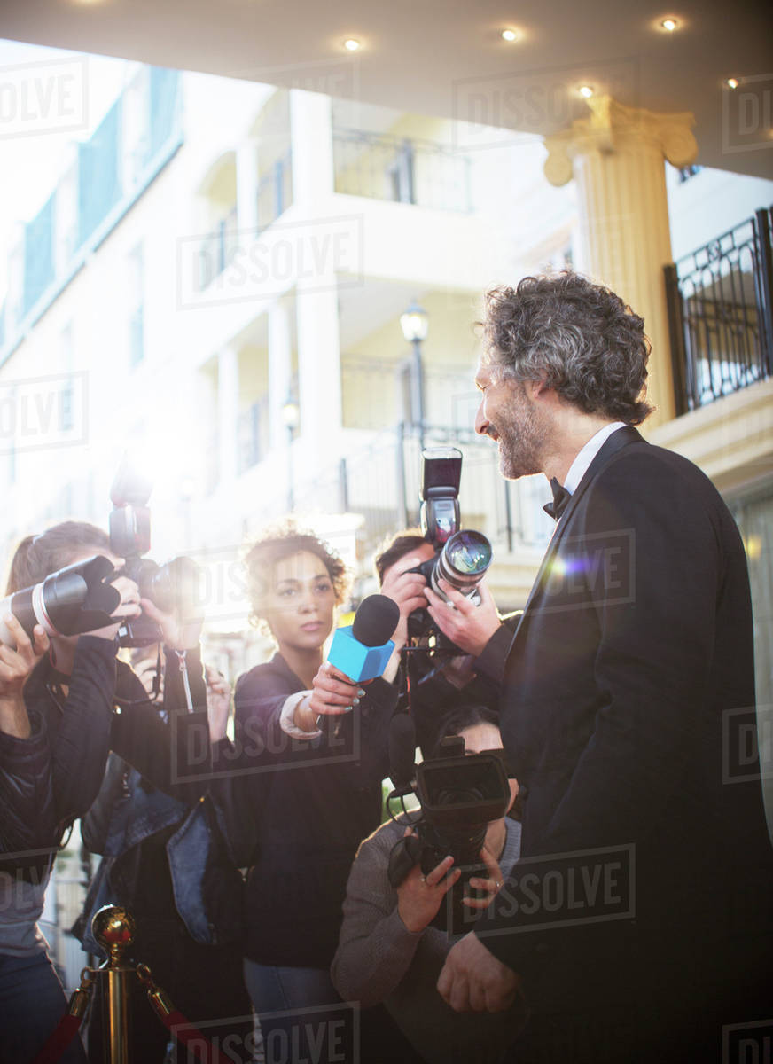 Celebrity being interviewed and photographed by paparazzi at event ...