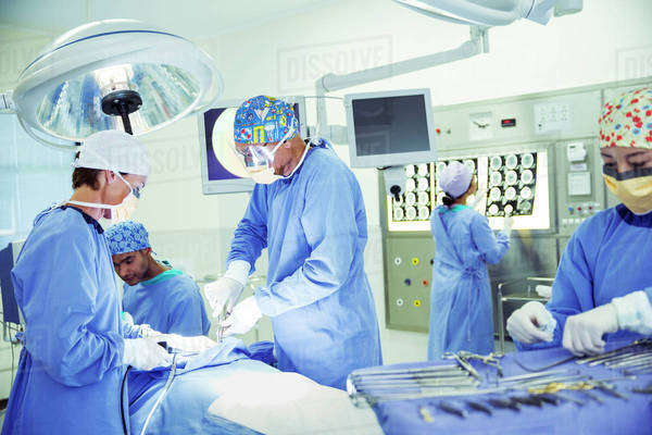 Surgeons performing surgery in operating room - Stock Photo - Dissolve