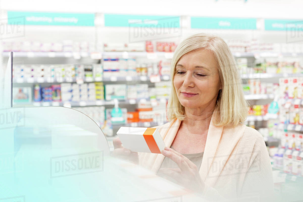 Customer reading label on box in pharmacy - Stock Photo - Dissolve