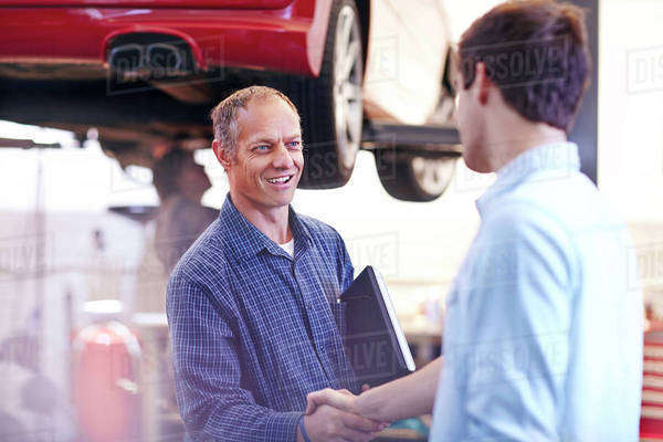 Mechanic and customer handshaking in auto repair shop - Stock Photo ...
