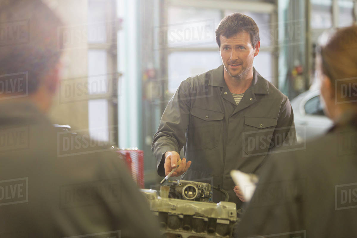 Mechanic explaining engine to students in auto repair shop - Royalty ...