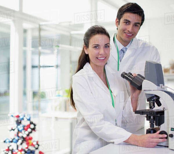 Portrait of smiling scientists using microscope in laboratory - Royalty ...