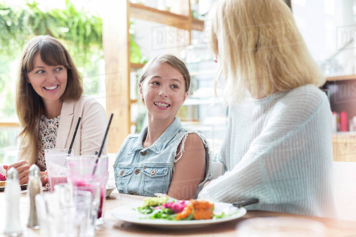 Women and girl eating lunch at cafe table - Stock Photo - Dissolve