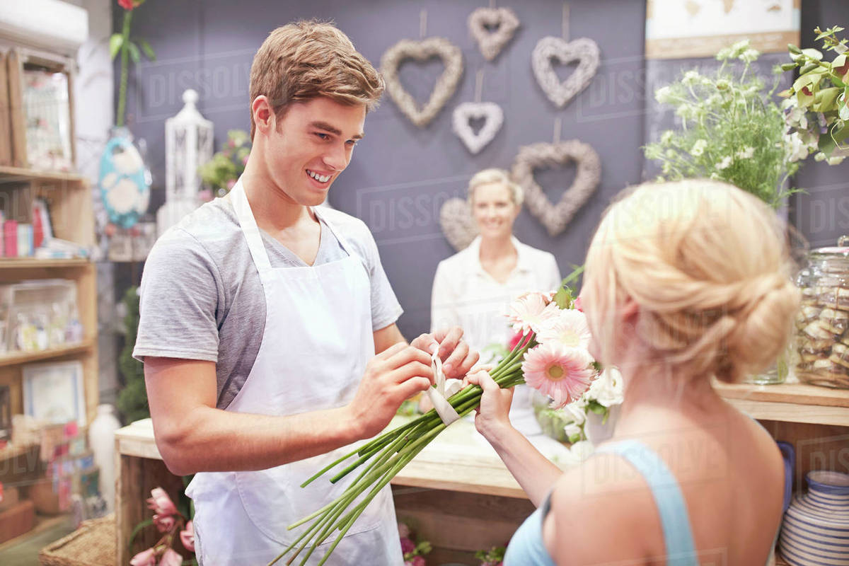 Florist tying flowers for woman in flower shop - Stock Photo - Dissolve