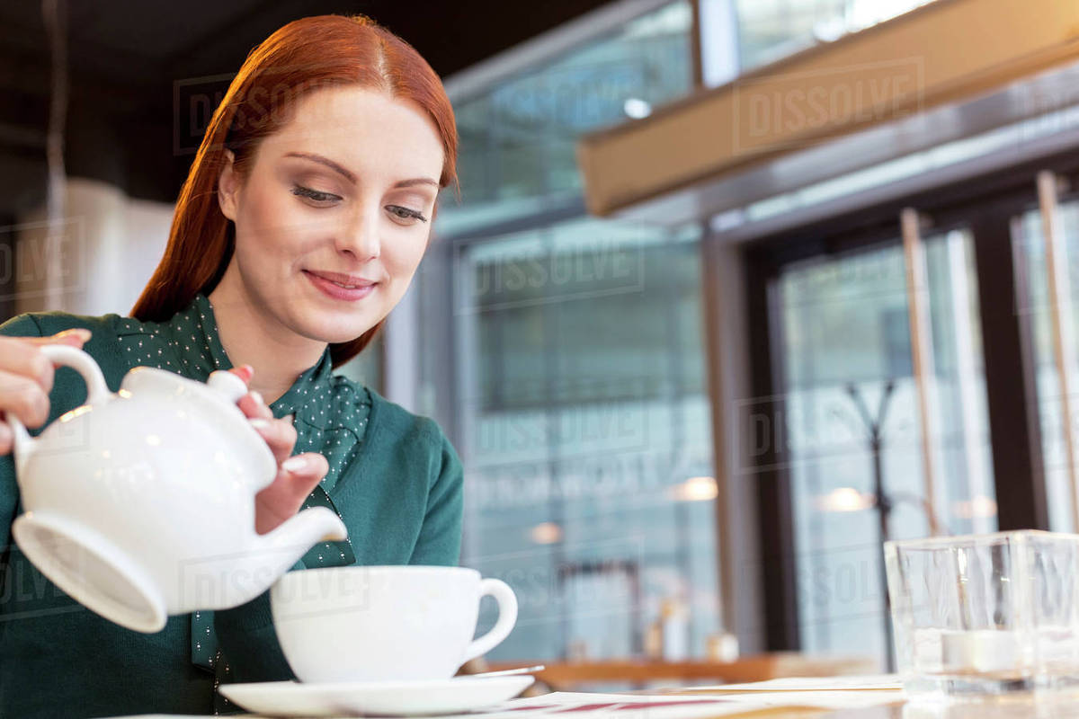 Smiling woman pouring tea in cafe - Stock Photo - Dissolve