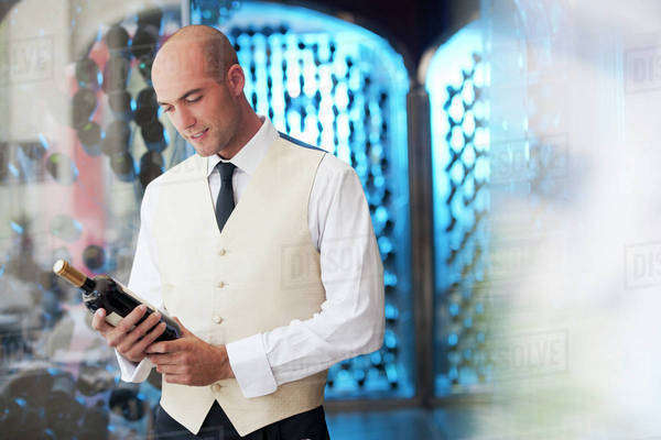 Waiter reading bottle of wine in kitchen - Royalty-free Stock Photo ...
