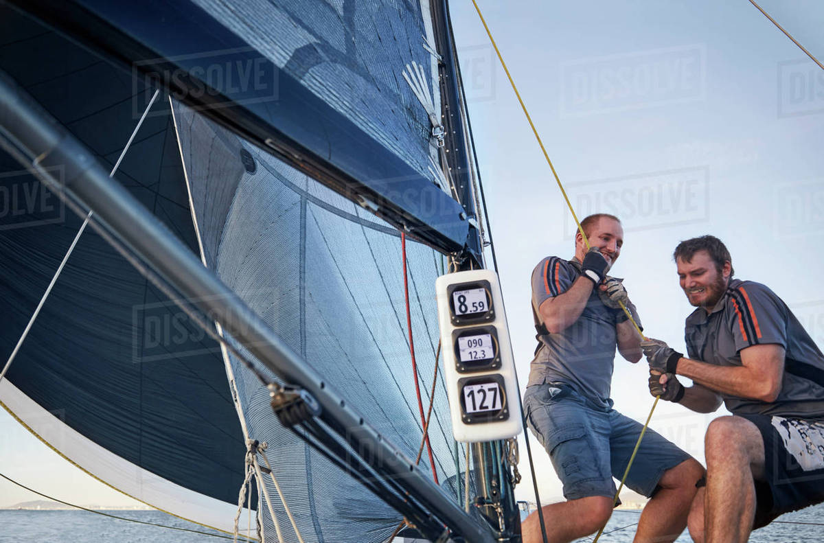 Men sailing pulling rigging equipment on sailboat - Stock Photo - Dissolve