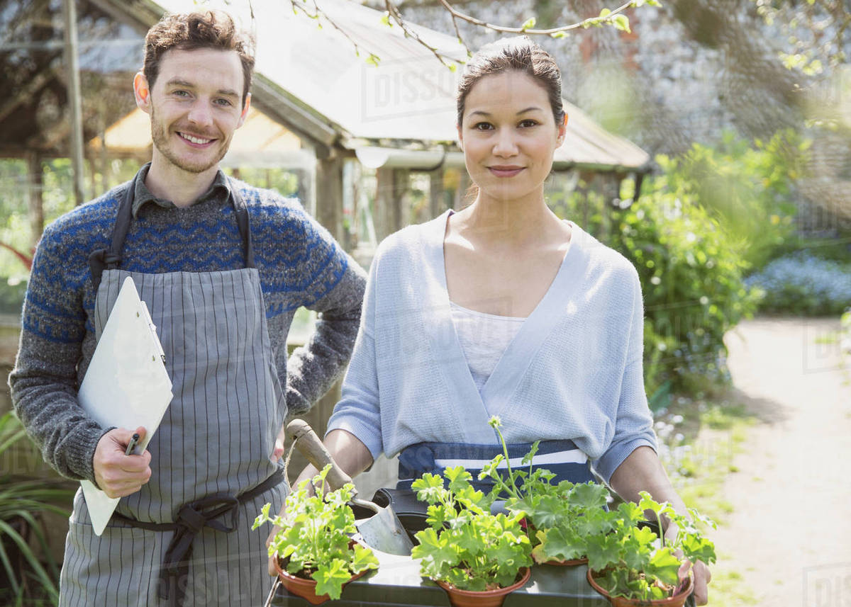 Portrait confident plant nursery workers with clipboard and potted ...