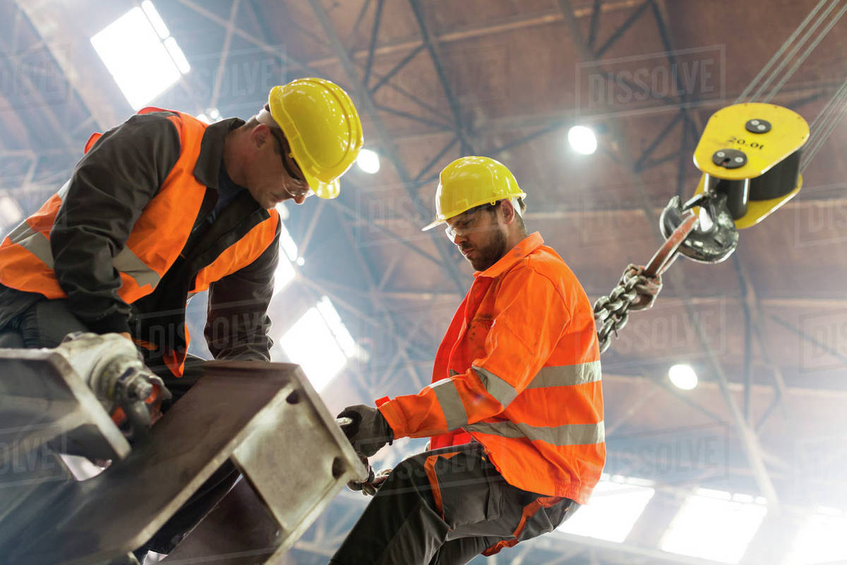 Steel workers fastening crane hook to steel in factory - Royalty-free ...