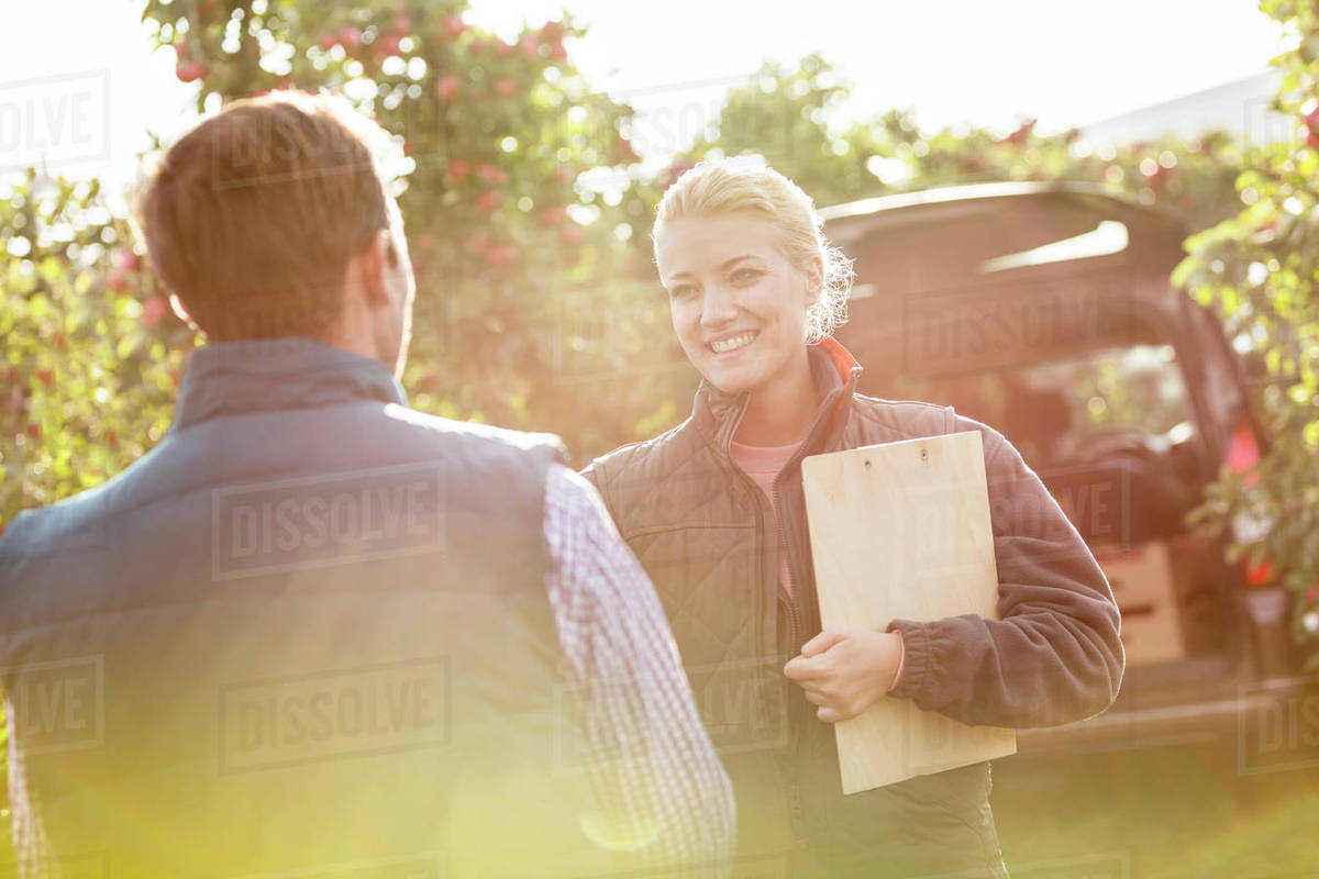 Smiling farmers talking in sunny apple orchard - Royalty-free Stock ...