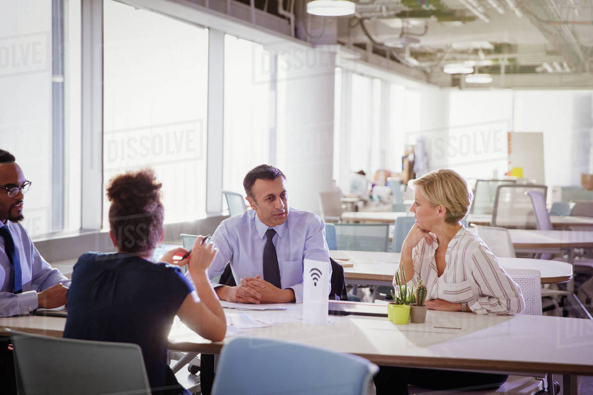 Business people talking at table in shared workspace - Stock Photo ...