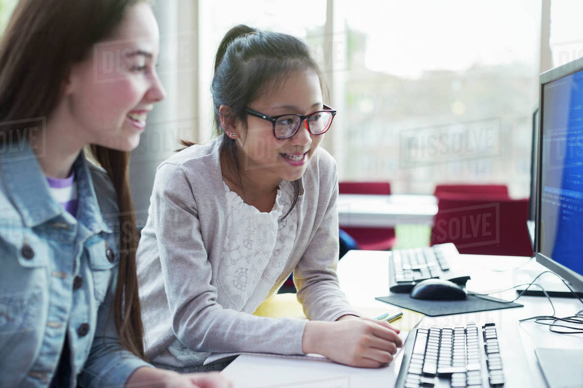 Girl students researching at computer in library - Stock Photo - Dissolve