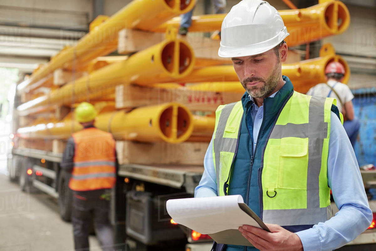 Male foreman reading paperwork on clipboard in factory - Stock Photo ...