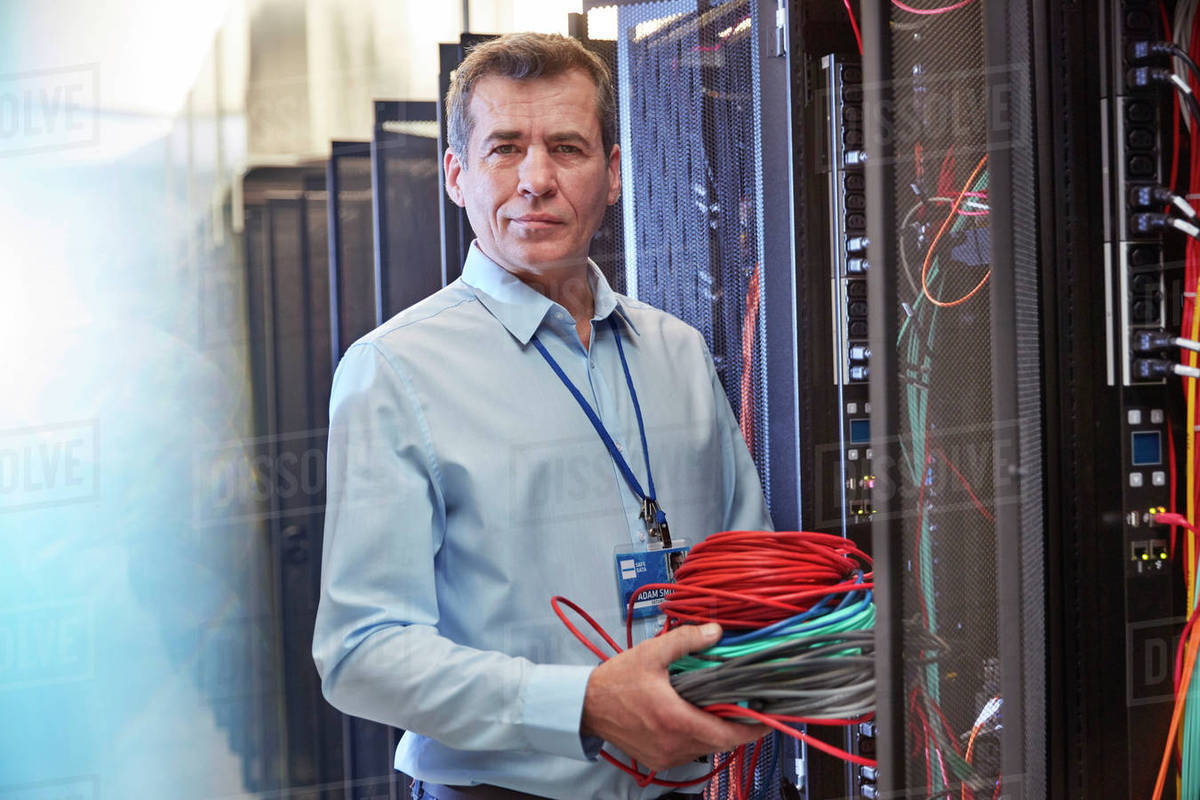 Portrait serious male IT technician holding cables in server room ...