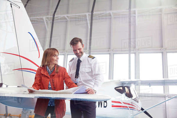 Pilot and engineer reviewing plans on airplane wing in hangar - Royalty ...