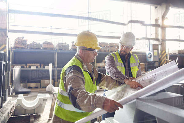 Steelworker and engineer reviewing blueprints in steel mill - Royalty ...