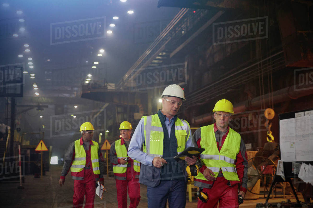 Supervisor and steelworkers walking and talking in steel mill - Royalty ...
