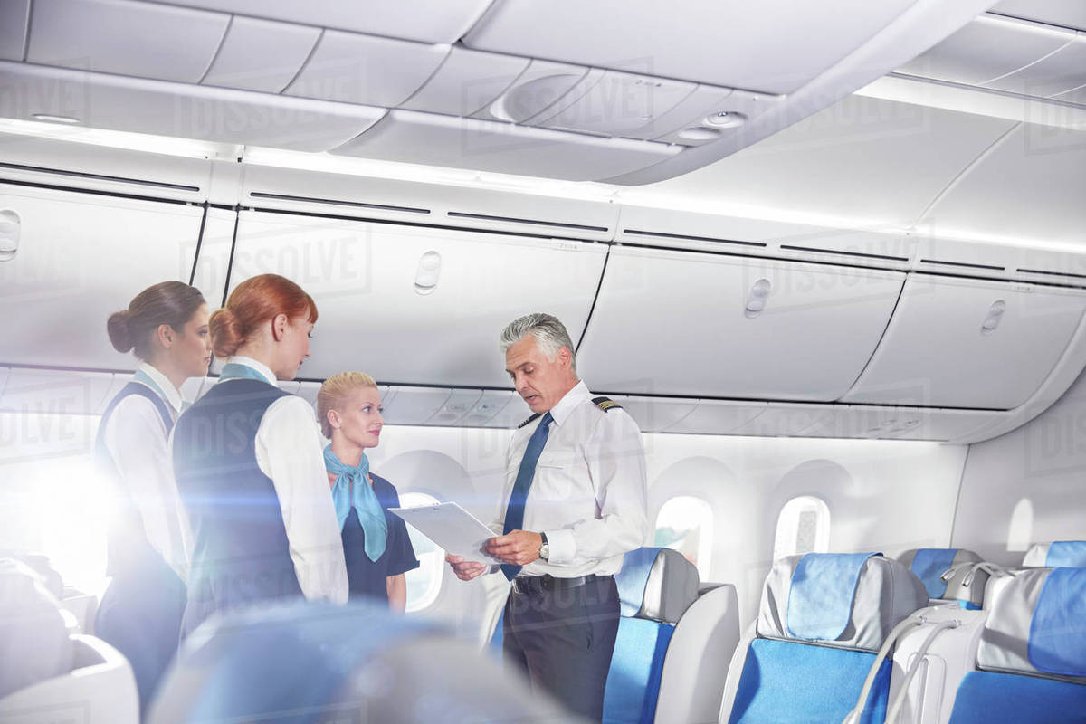 Pilot and flight attendants talking, preparing on airplane - Royalty ...