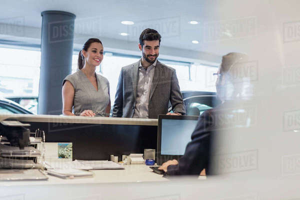 Couple at reception desk in car dealership showroom - Stock Photo ...