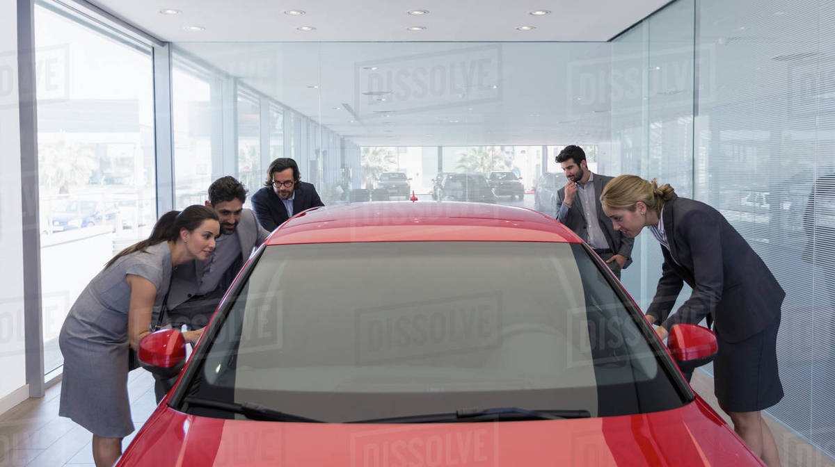 Customers looking at new car in car dealership showroom - Royalty-free ...