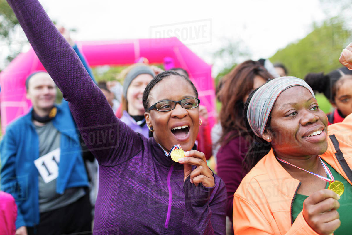 Enthusiastic female runners with medals cheering, celebrating at ...