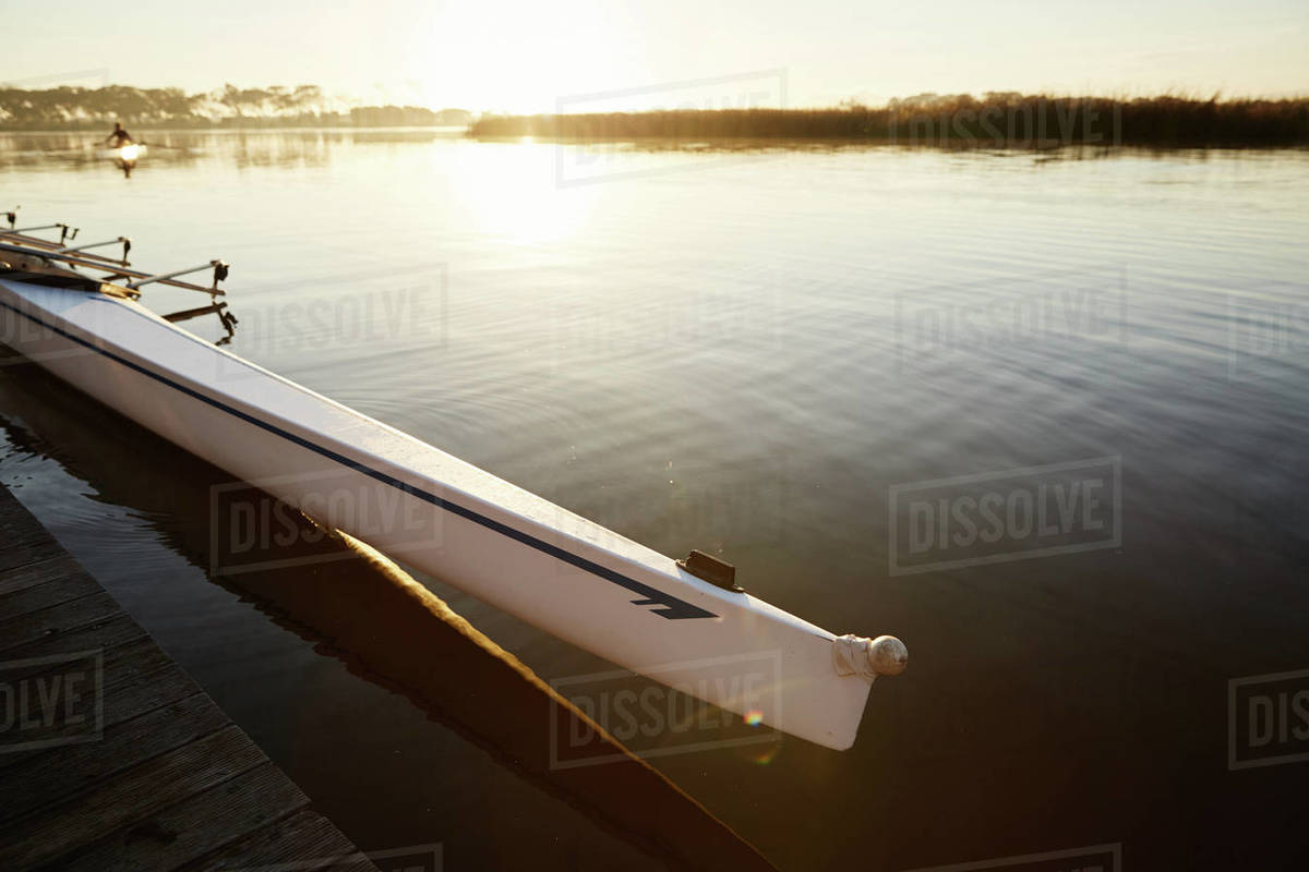 Scull at dock on tranquil sunrise lake - Stock Photo - Dissolve