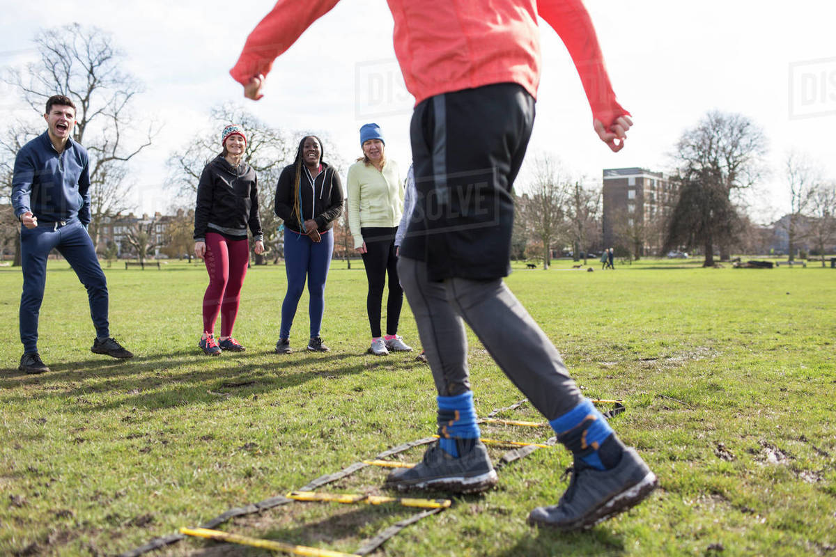 Team watching man doing speed ladder drill in sunny park - Stock Photo ...